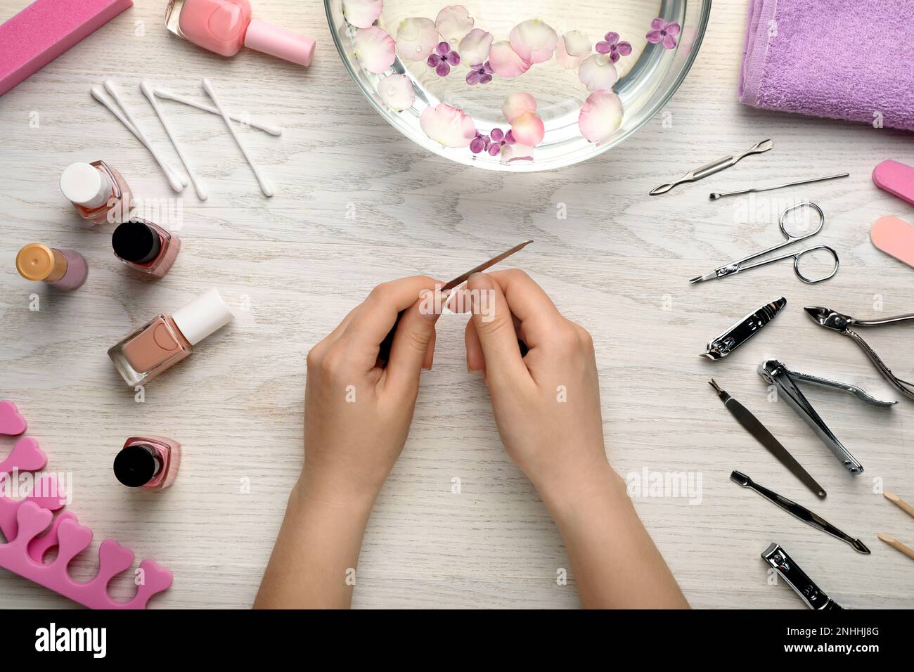 Woman filling nail at white wooden table, top view. Manicure procedure ...