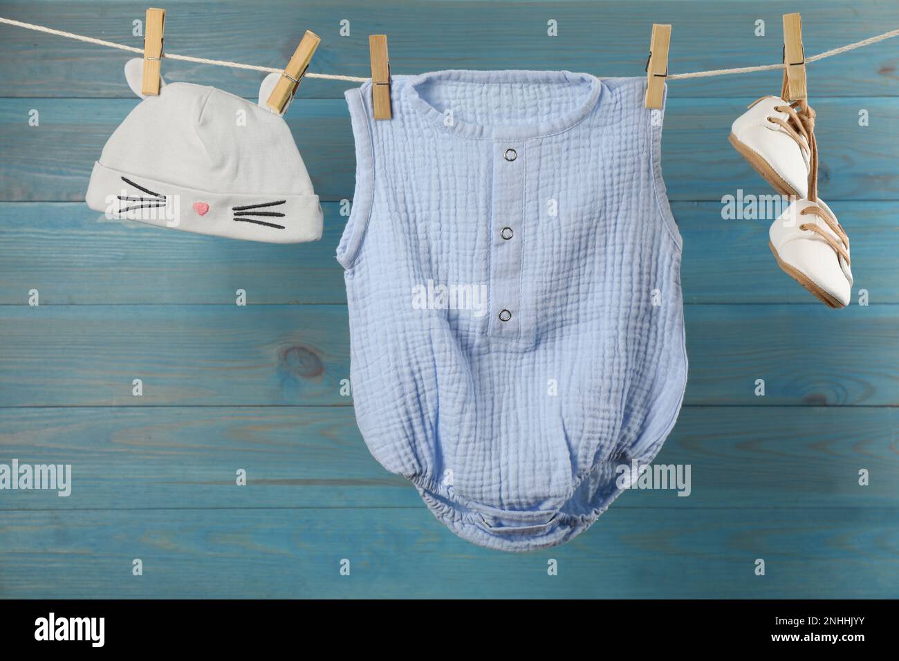 Baby clothes hanging on washing line near light blue wooden wall Stock ...