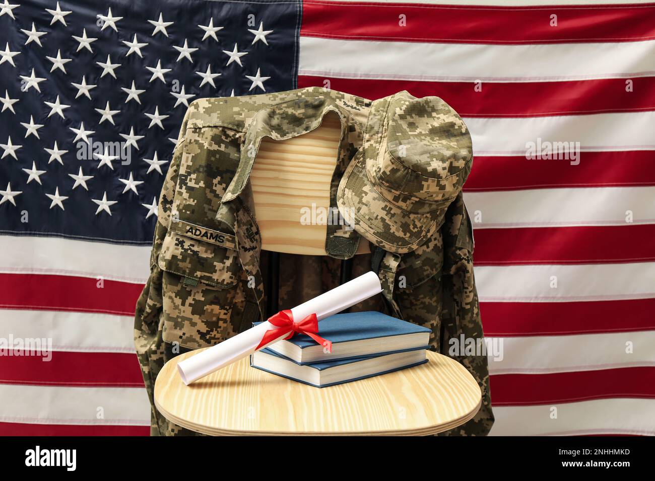 Diploma, books and soldier uniform on wooden chair near flag of United ...