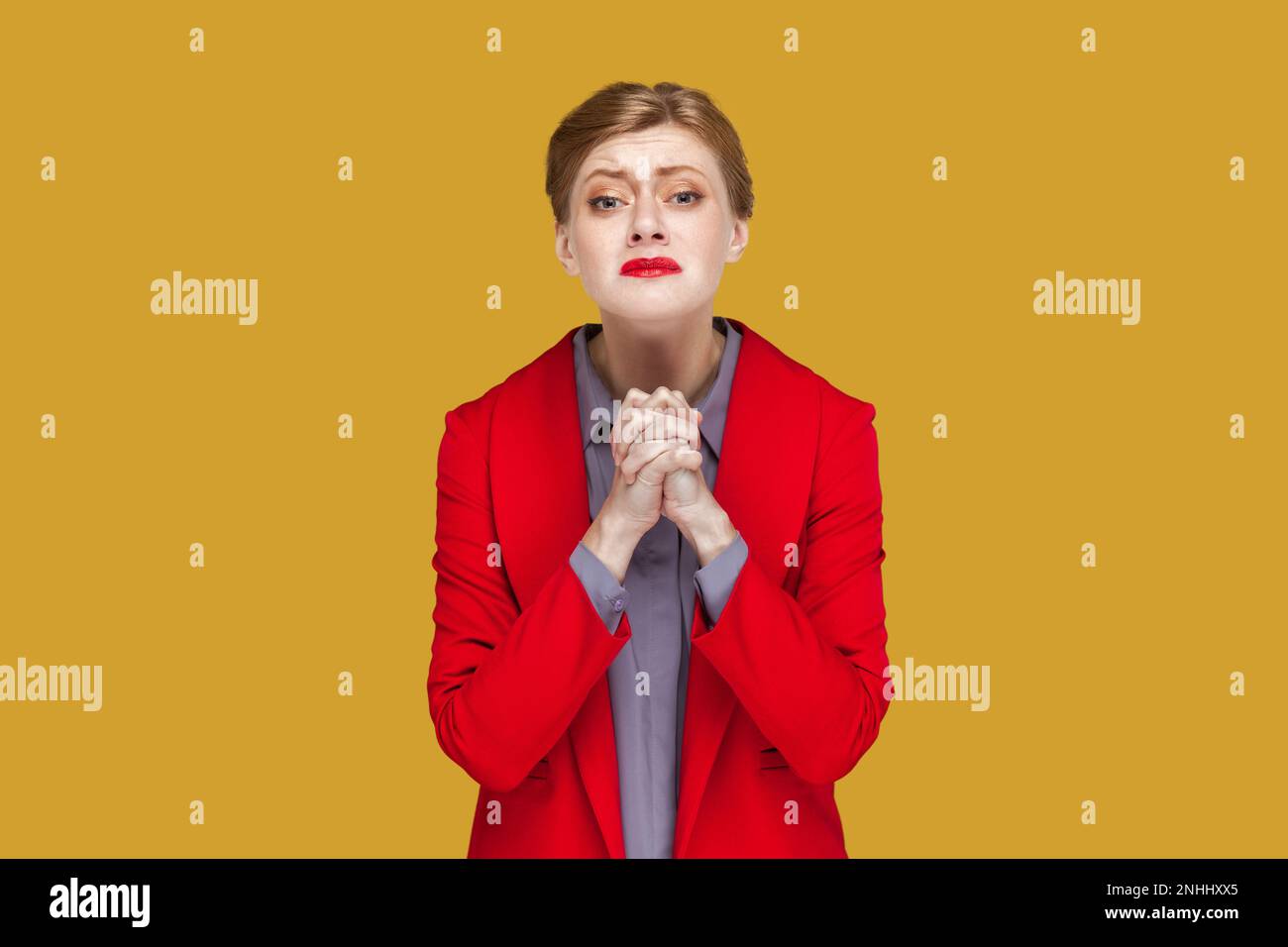 Portrait of hopeful woman with red lips standing with hands together ...