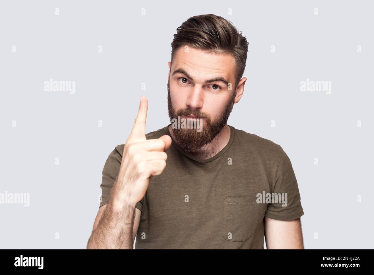 Portrait of serious attractive bearded man wearing dark green T-shirt ...