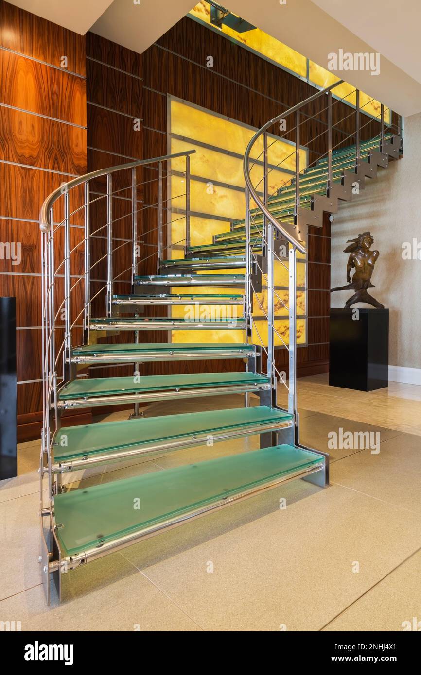 Steel and tempered glass twisting staircase against exotic wood ...