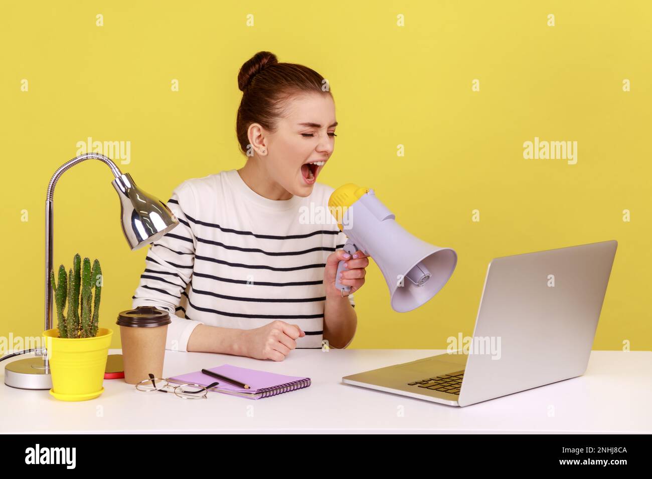 Portrait of young excited woman screaming loudly in megaphone ...