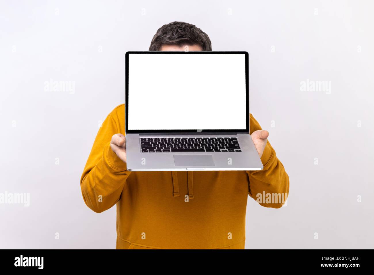 Unknown man hiding face behind laptop with empty display and presenting ...