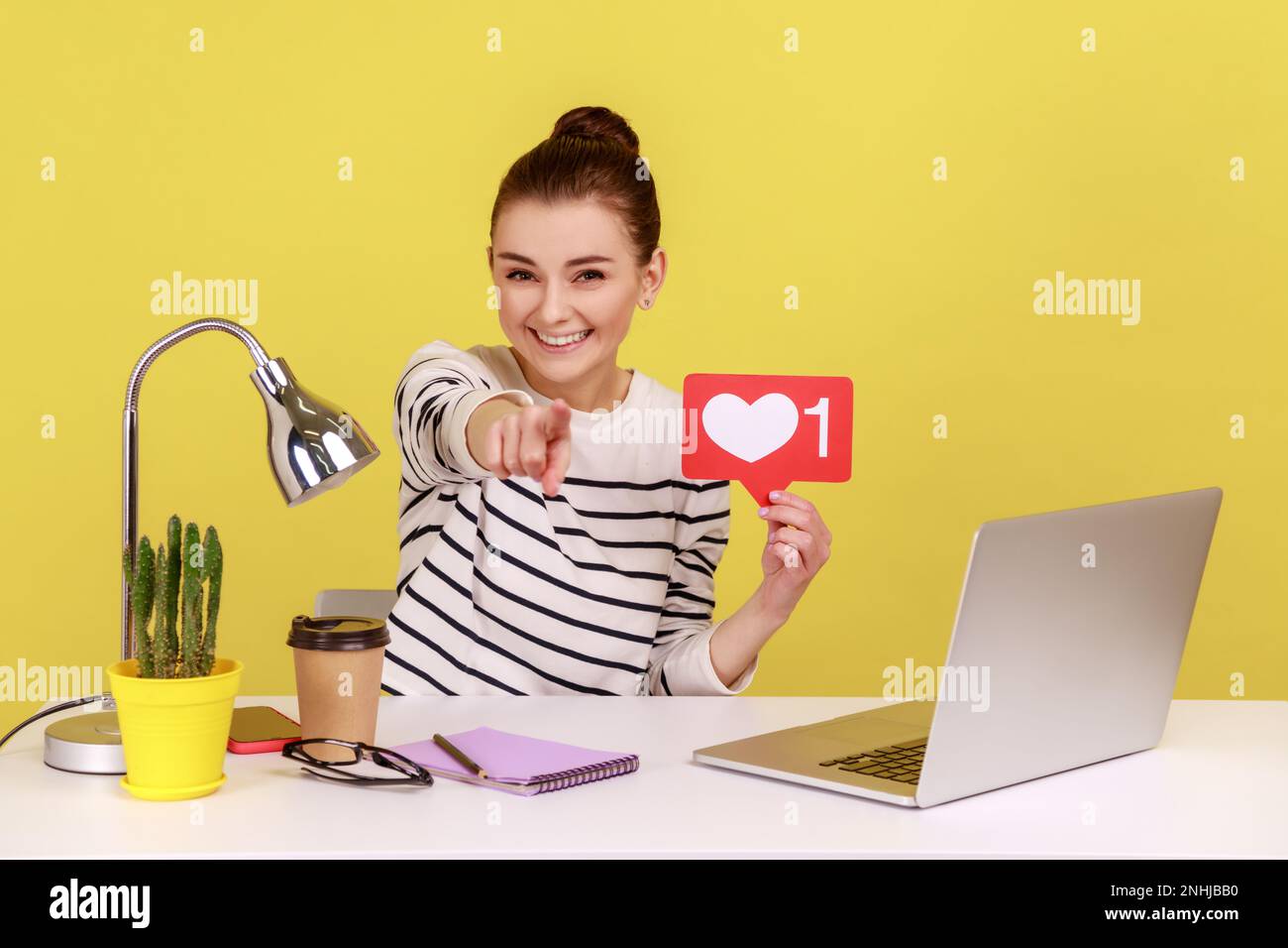 Hey you, click here. Happy woman blogger sitting on workplace holding ...