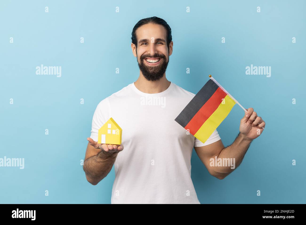 Portrait of happy handsome man with beard wearing white T-shirt holding ...