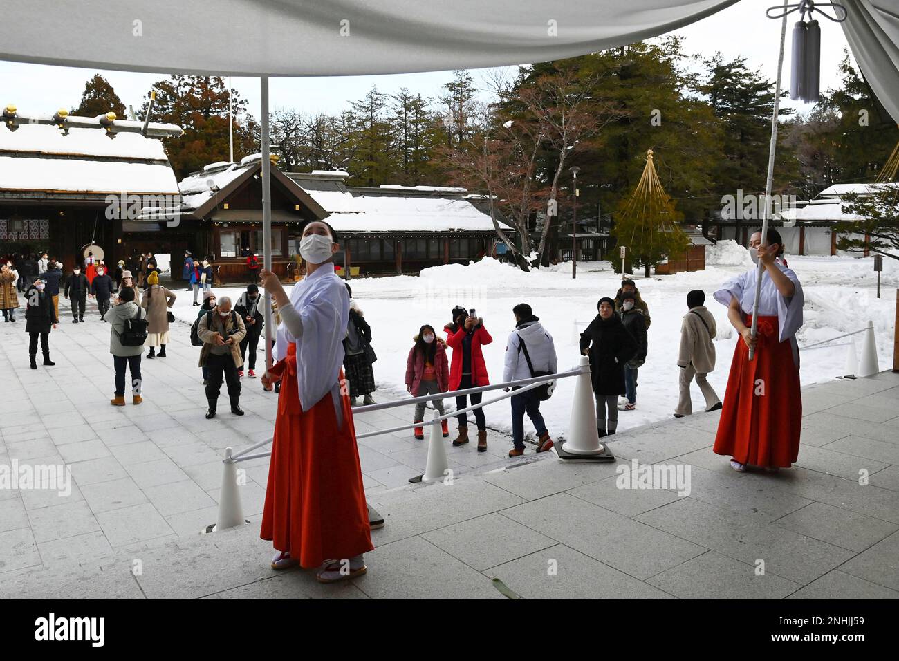 Miko, Shrine maiden, wearing face masks perform a susuharai by bamboo ...