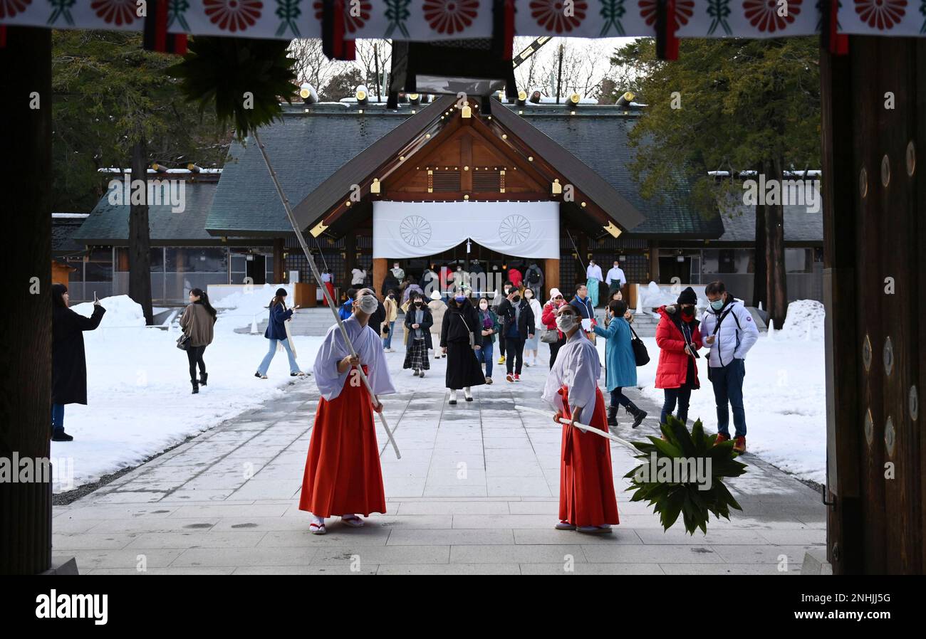 Miko, Shrine maiden, wearing face masks perform a susuharai by bamboo ...