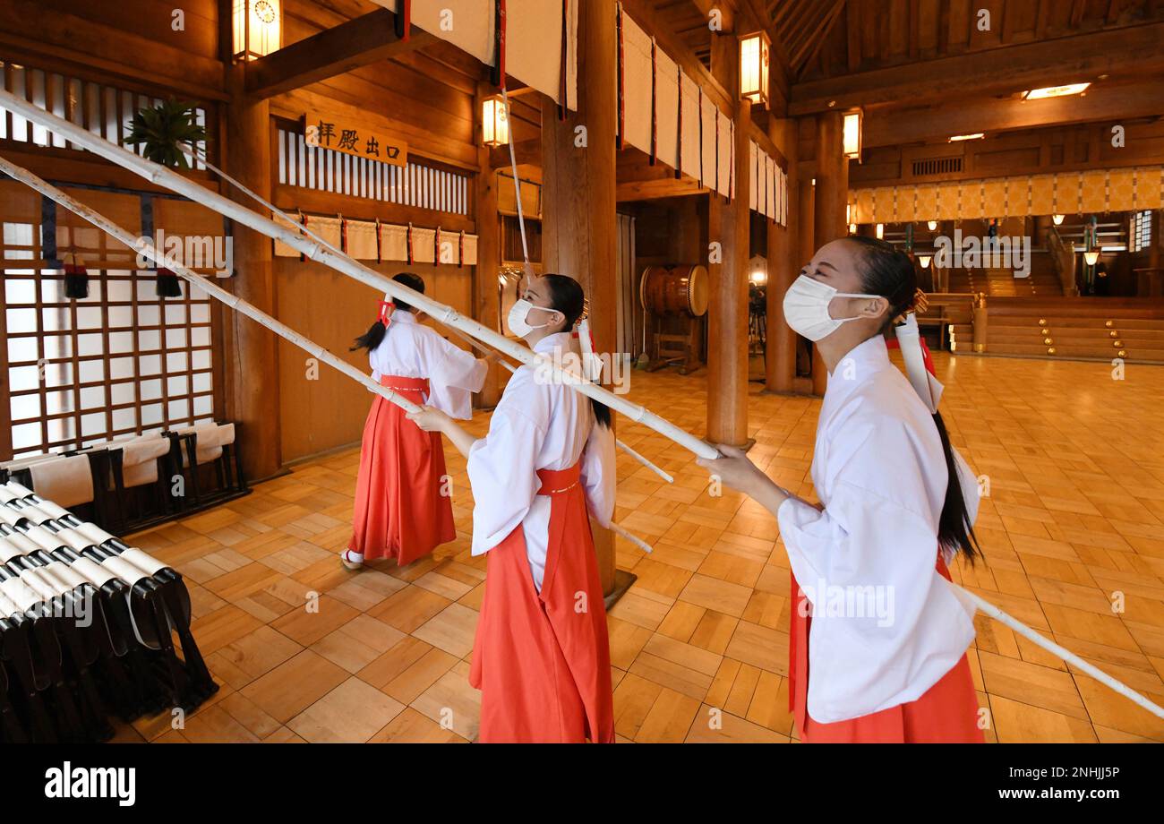 Miko, Shrine maiden, wearing face masks perform a susuharai by bamboo ...