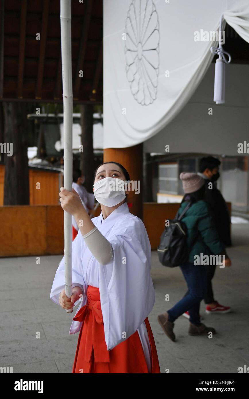 Miko, Shrine maiden, wearing face masks perform a susuharai by bamboo ...