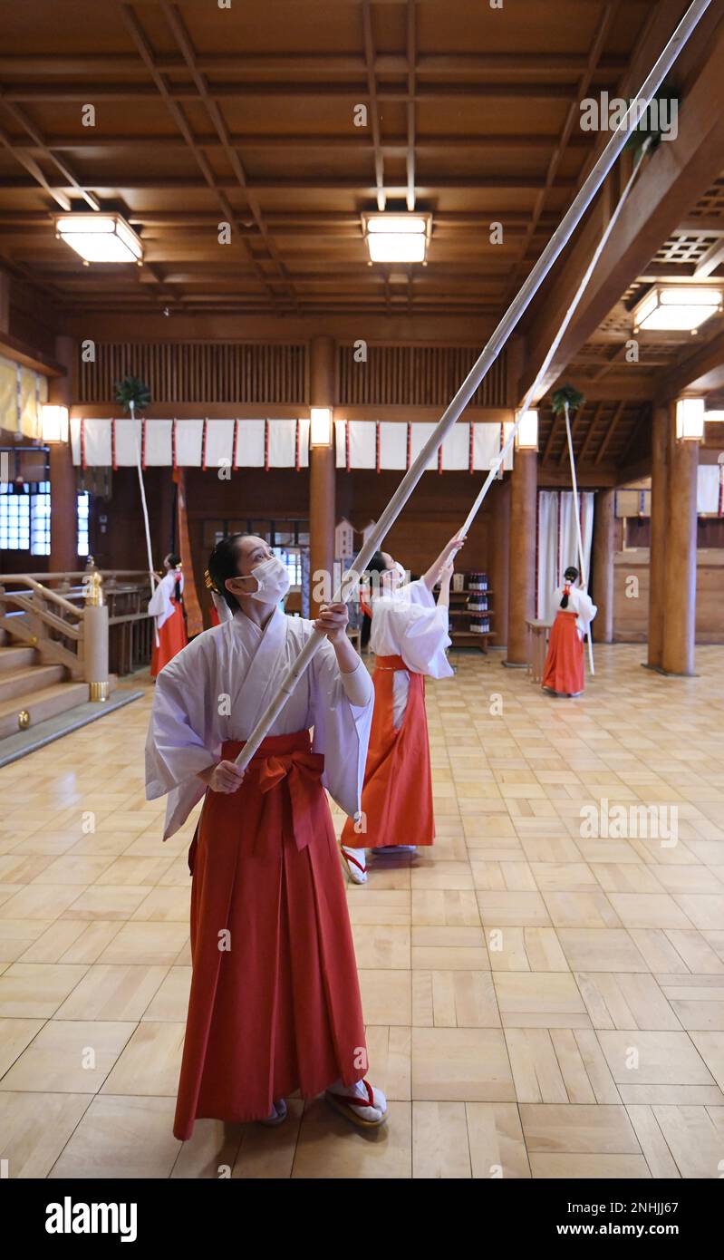 Miko, Shrine maiden, wearing face masks perform a susuharai by bamboo ...