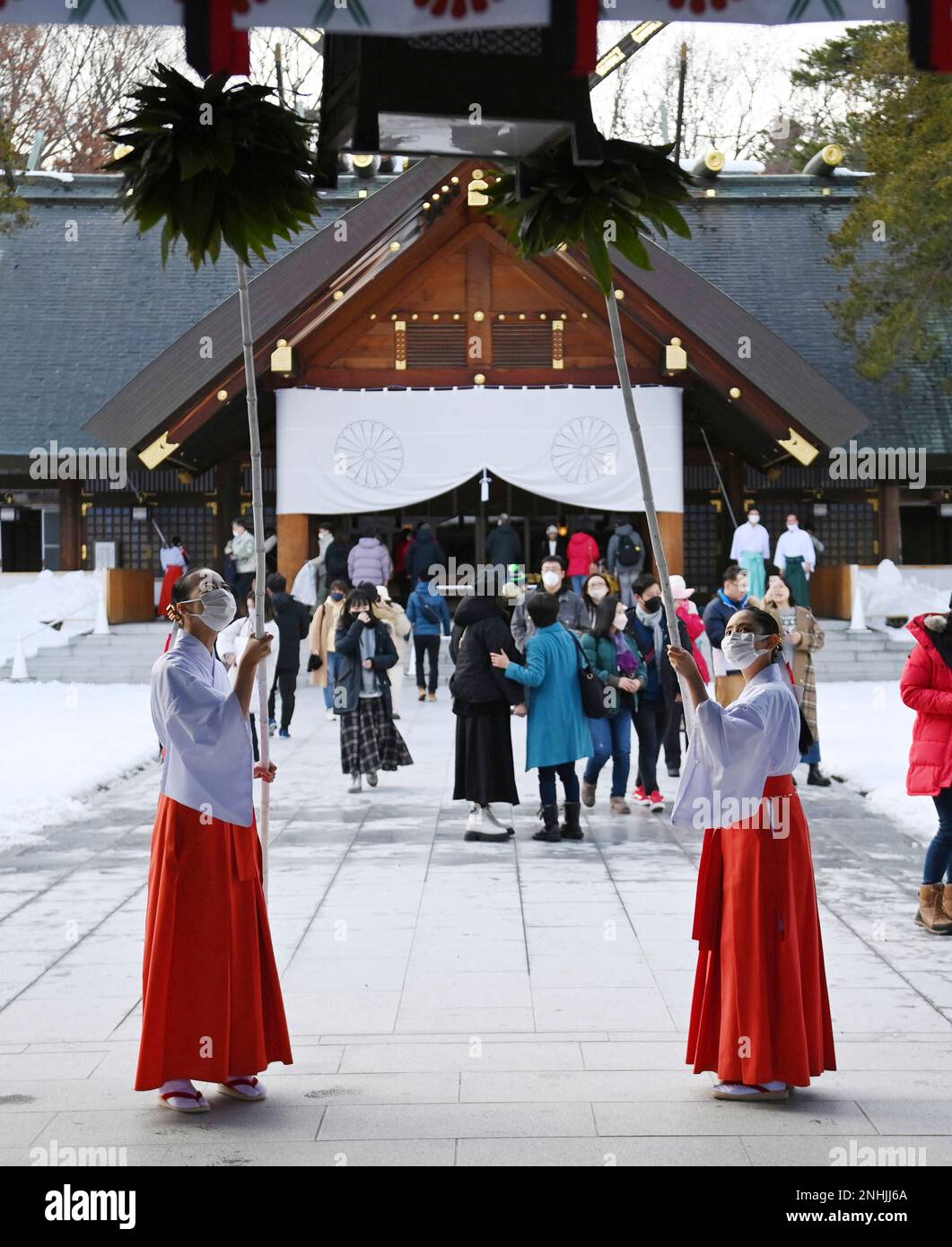 Miko, Shrine maiden, wearing face masks perform a susuharai by bamboo ...