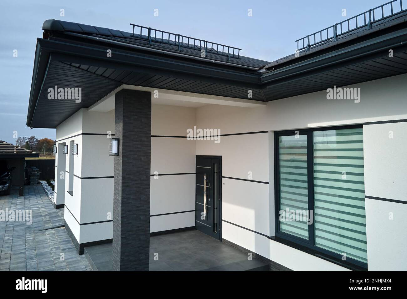 Corner of modern house with shingled roof and big window with closed ...
