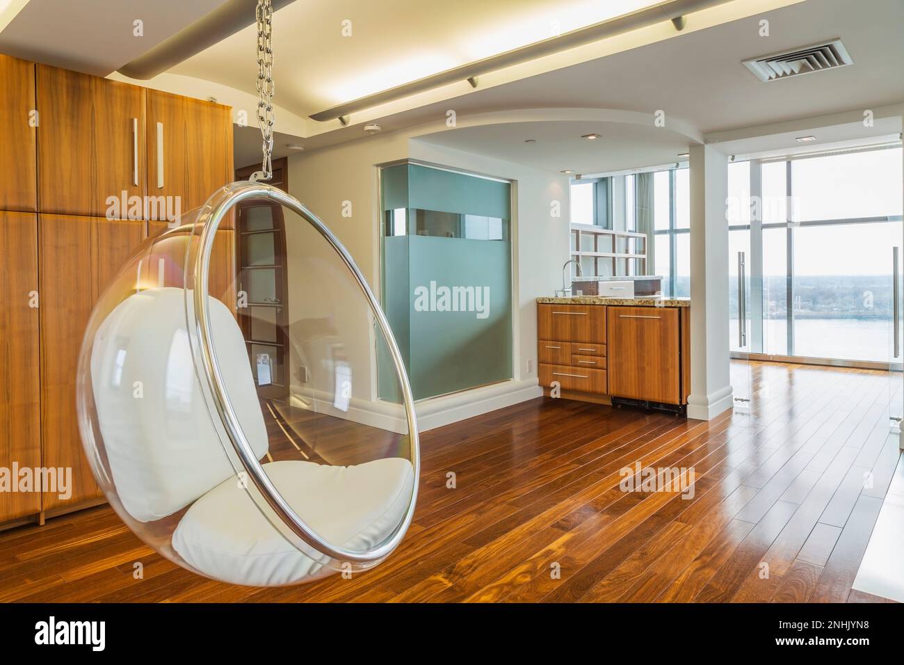 Clear plastic half-sphere chair suspended from the ceiling in home ...