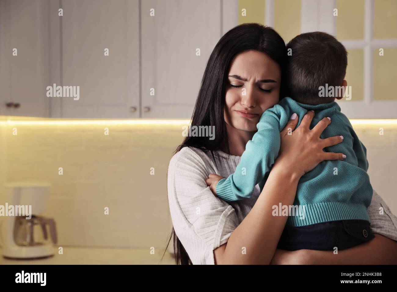 Depressed single mother with child in kitchen, space for text Stock ...