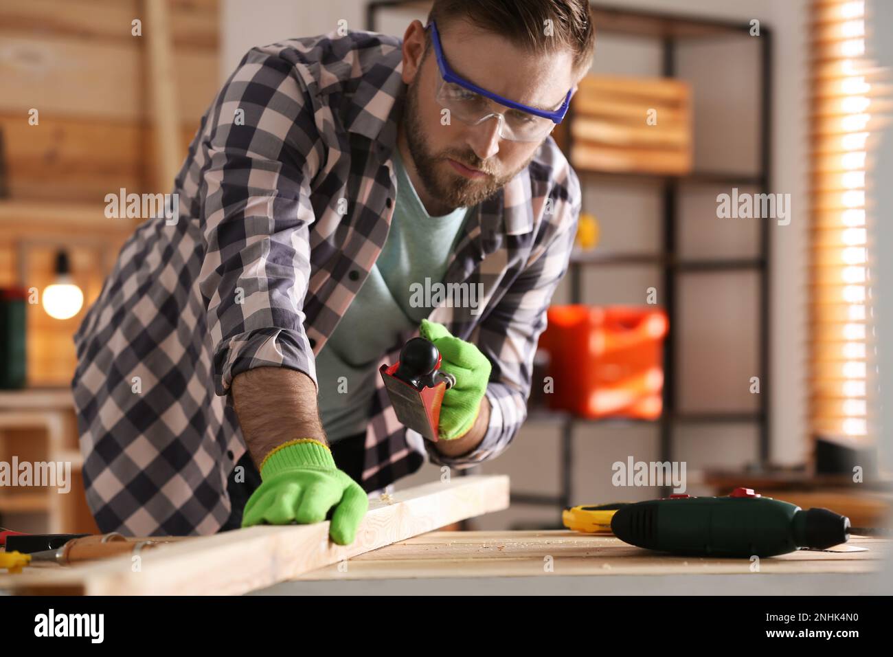 Carpenter shaping wooden bar with hand plane at table in workshop Stock ...
