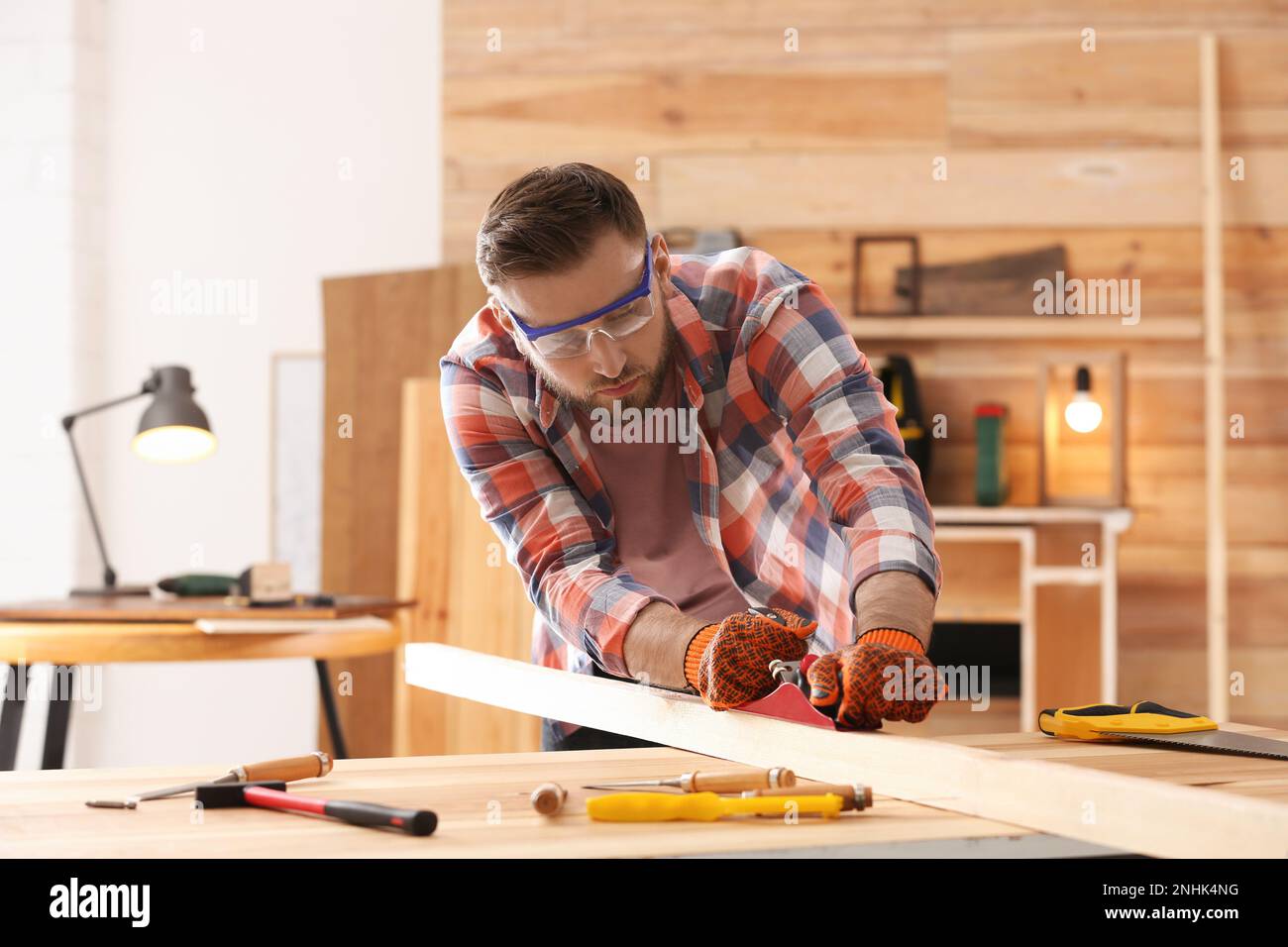 Carpenter shaping wooden bar with hand plane at table in workshop Stock ...