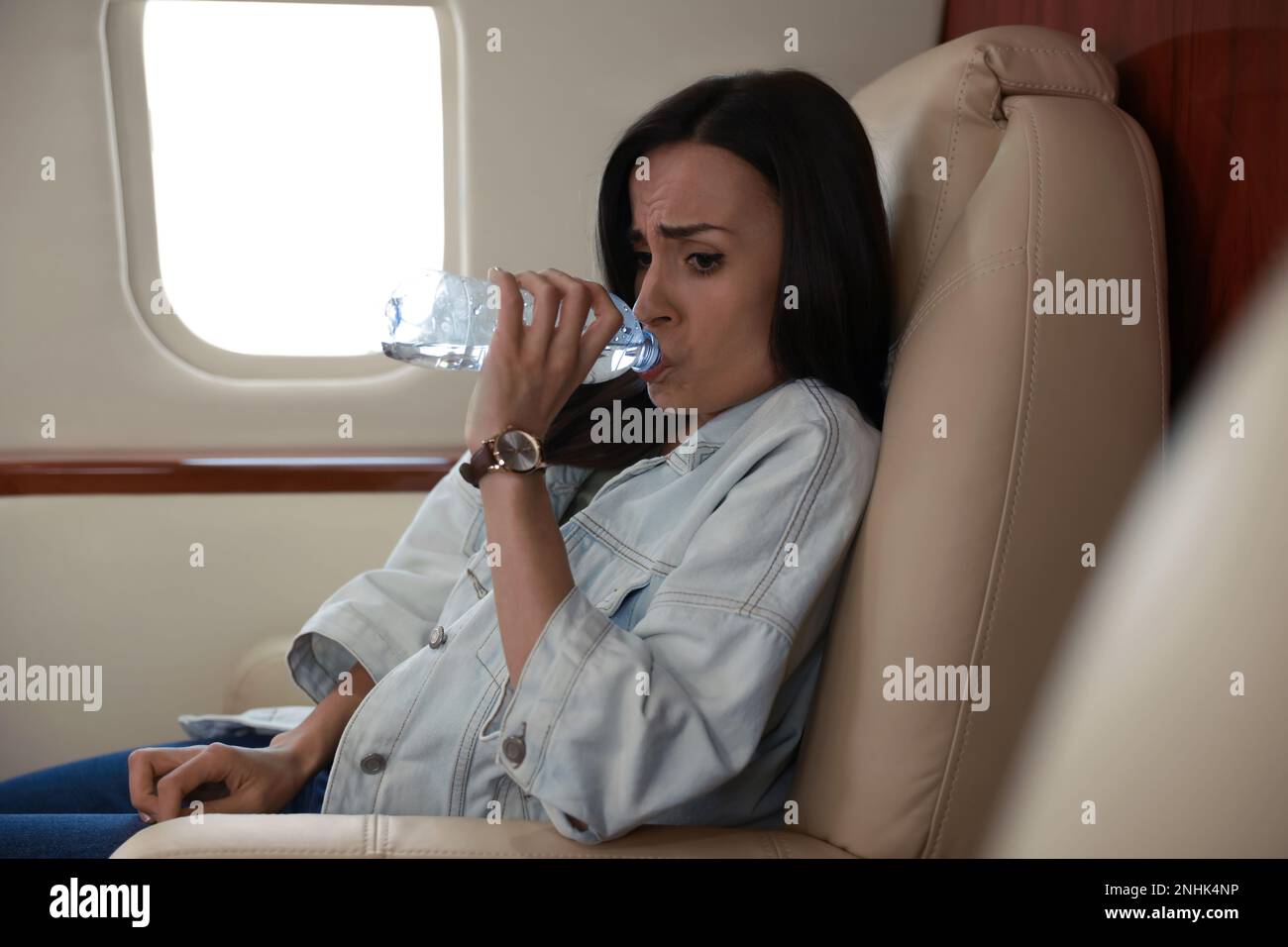 Nervous young woman with aviophobia drinking water in airplane Stock ...