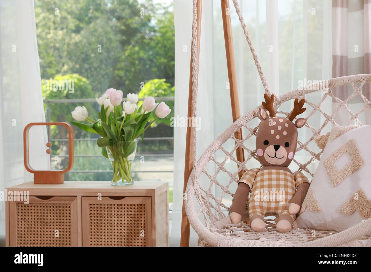 Swing chair with toy reindeer near window indoors. Interior design ...