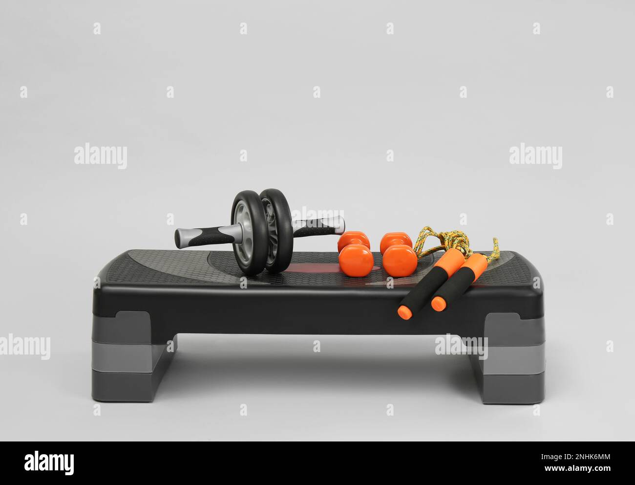 Step platform, skipping rope, dumbbells and abdominal wheel on light ...