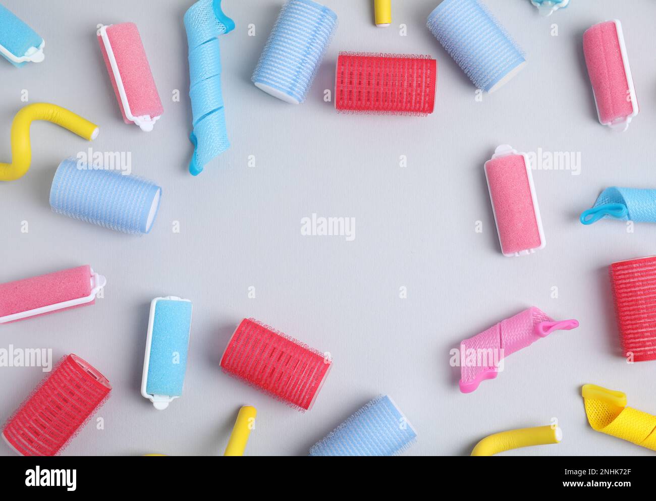 Frame of different hair curlers on light grey background, flat lay ...