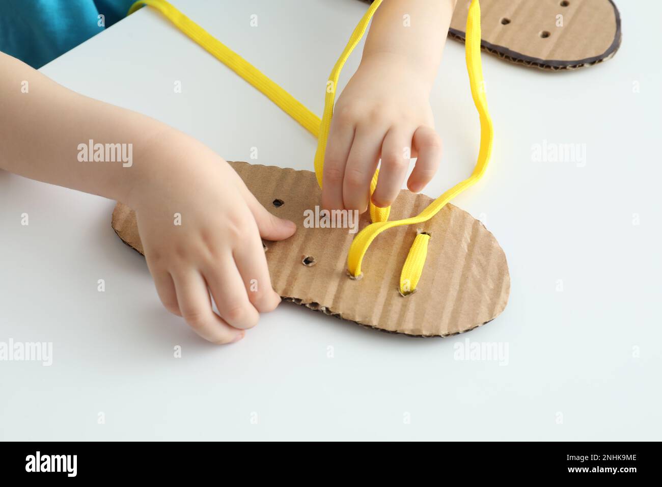 Little boy tying shoe lace using training cardboard template at white ...