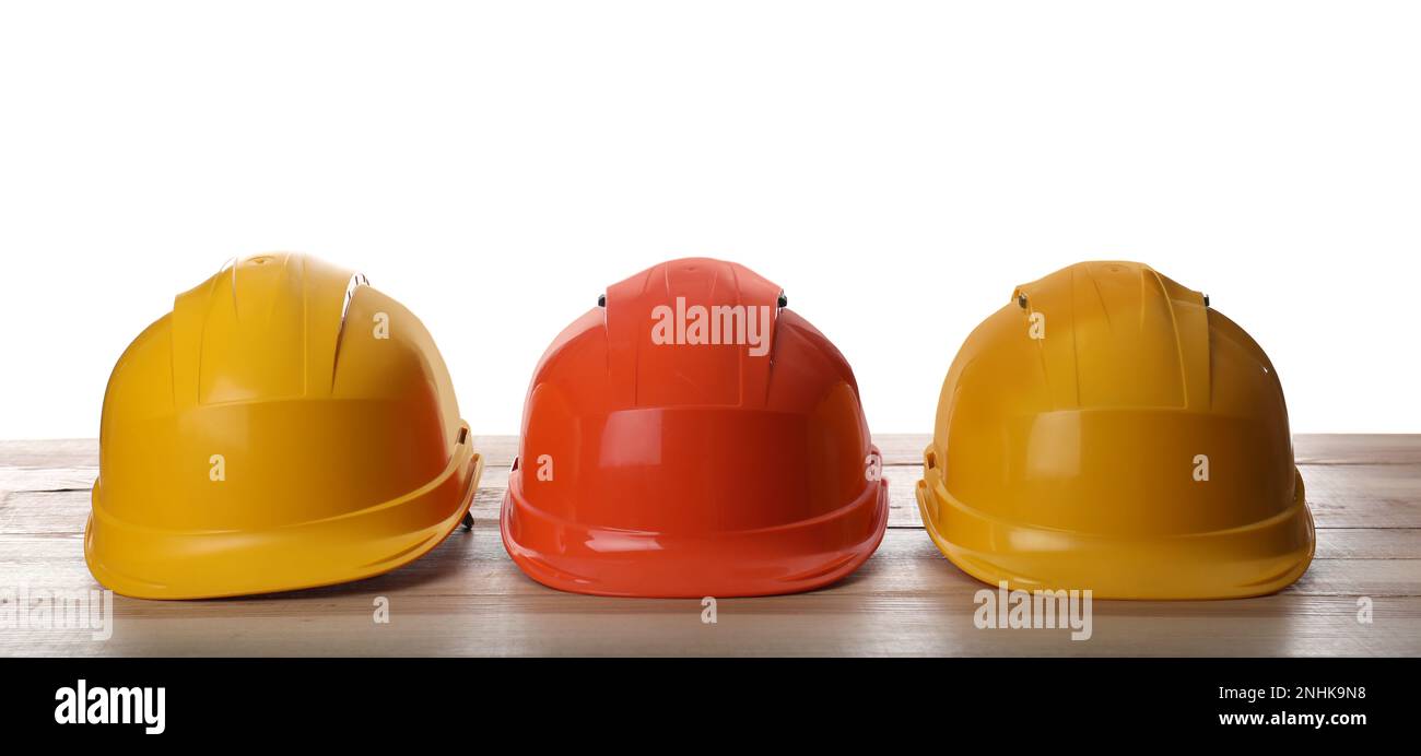 Different hard hats on wooden table against white background Stock ...