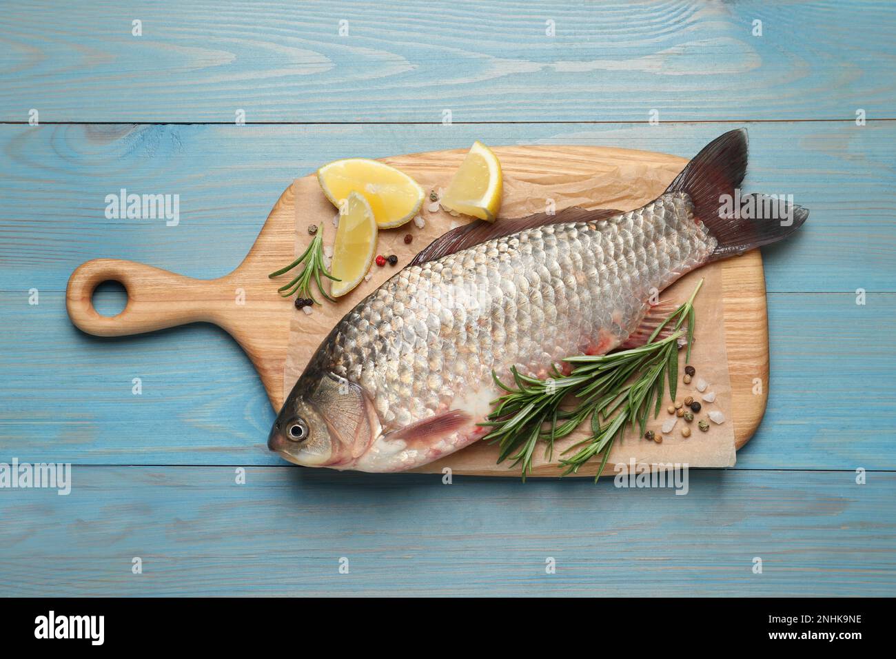 Fresh raw crucian carp and ingredients on light blue wooden table, top ...