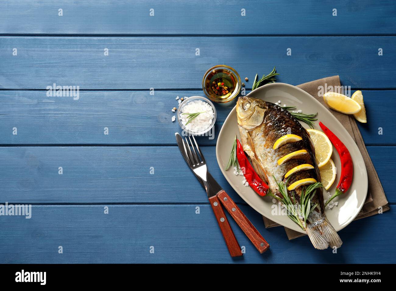Tasty homemade roasted crucian carp served on blue wooden table, flat ...