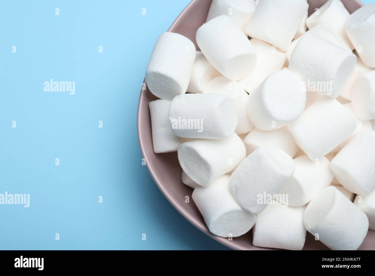 Delicious puffy marshmallows on light blue background, top view. Space ...