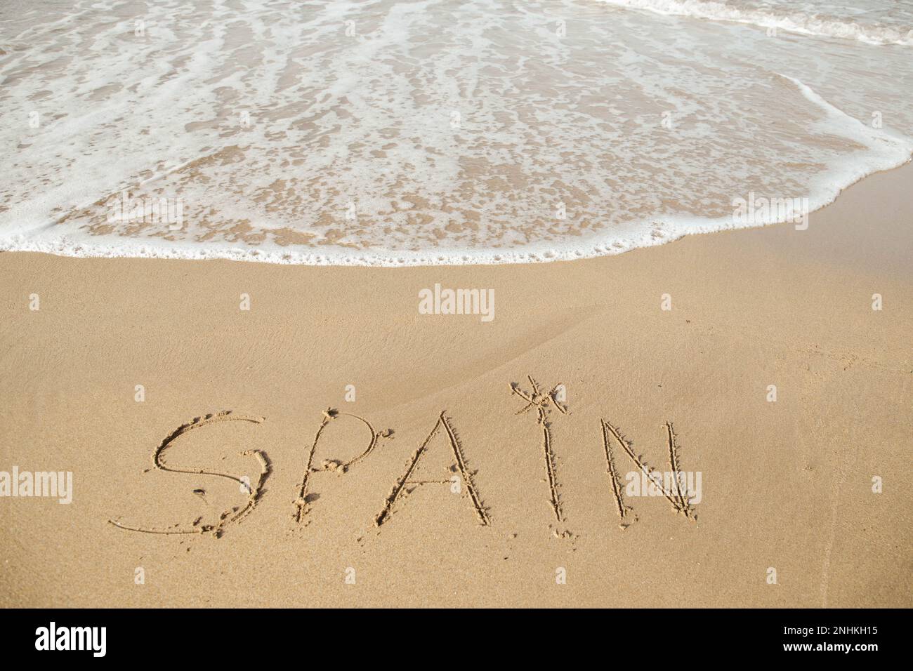 Spain lettering on the beach with wave and clear blue sea Stock Photo ...