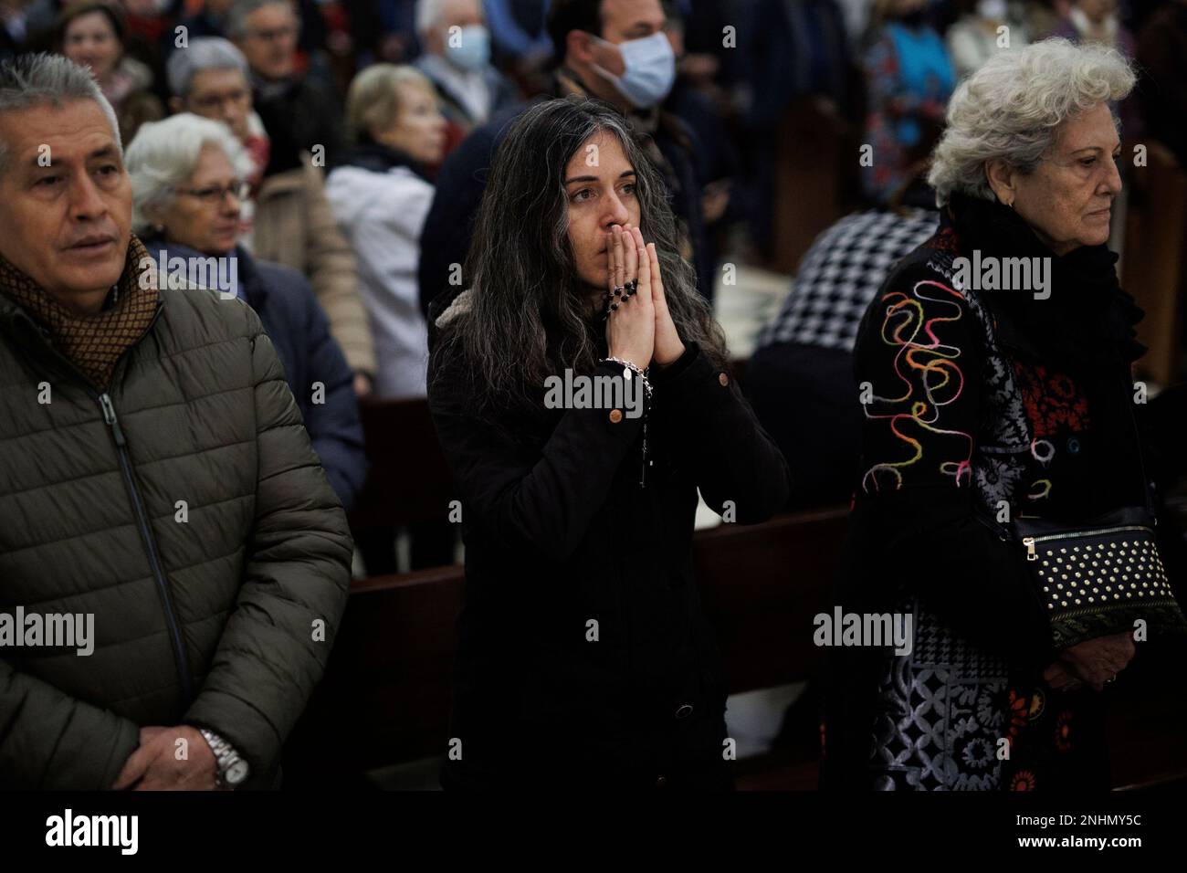 A parishioner joins hands while praying at a solemn mass in honor of ...