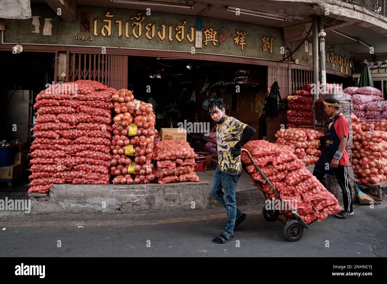A Myanmarese (Burmese) migrant worker pulling a trolley laden with ...