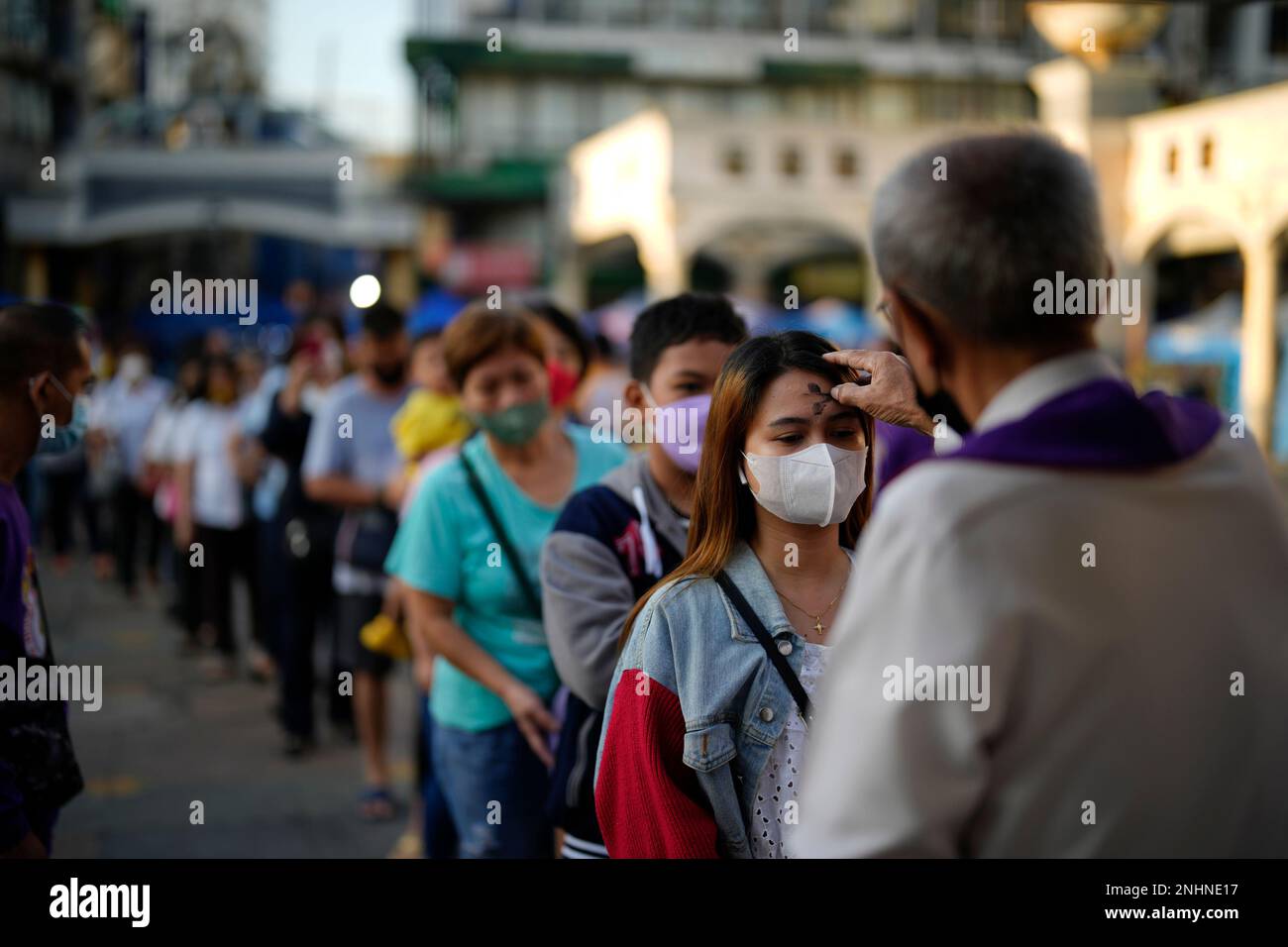 A lay minister places ash on the forehead of a devotees during Ash ...