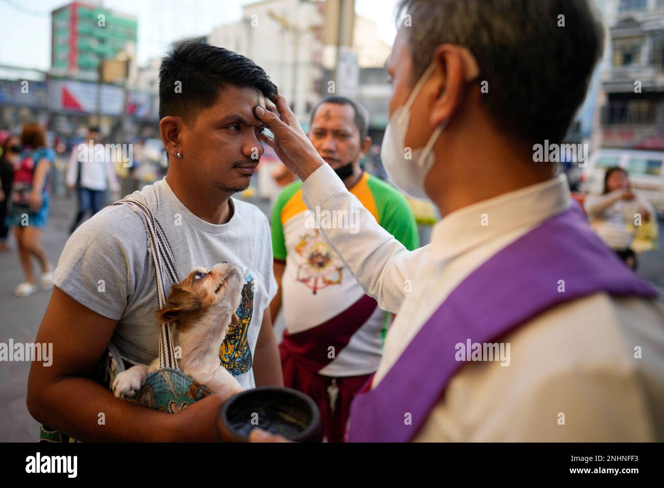 A lay minister places ash on the forehead of a devotee during Ash ...