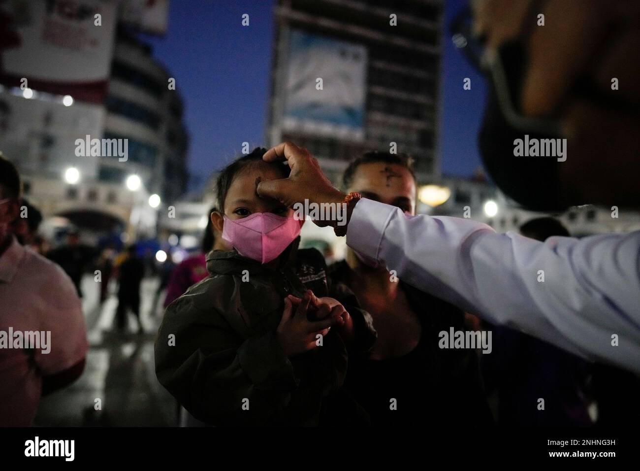 A lay minister places ash on the forehead of a child during Ash ...