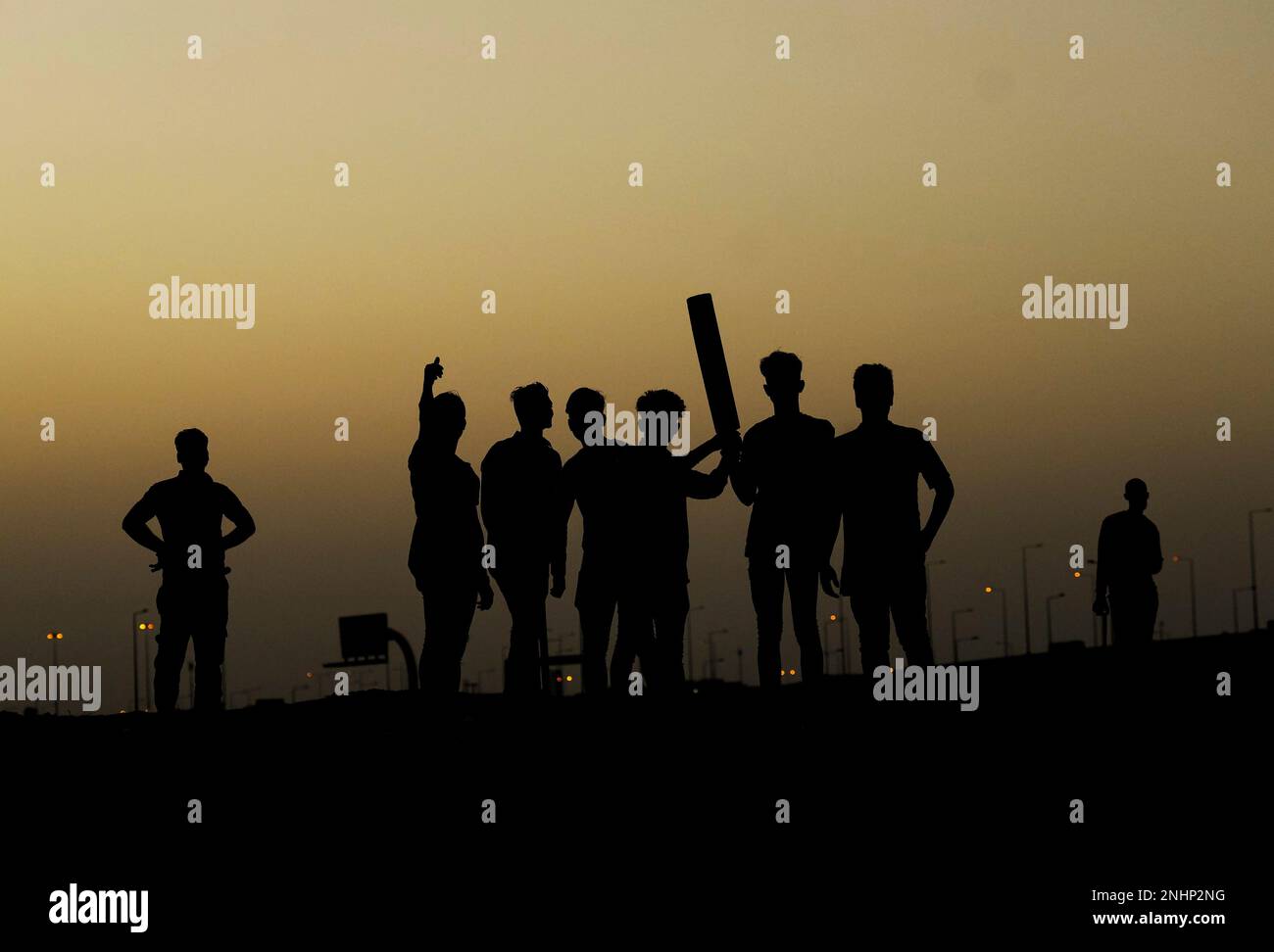 Migrant workers play cricket before watching soccer on a big projection ...
