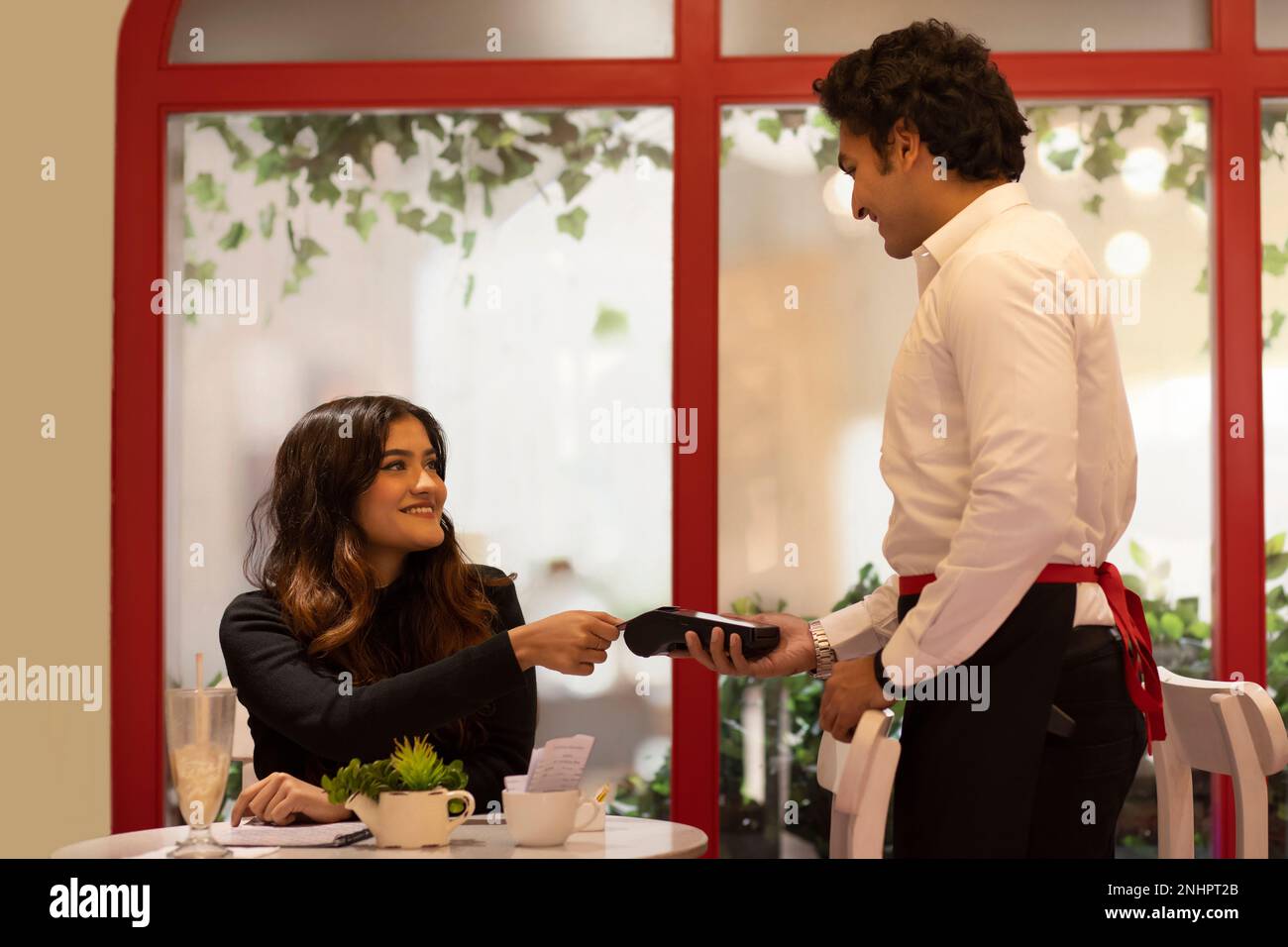 Woman giving credit card to waiter for payment at café Stock Photo - Alamy