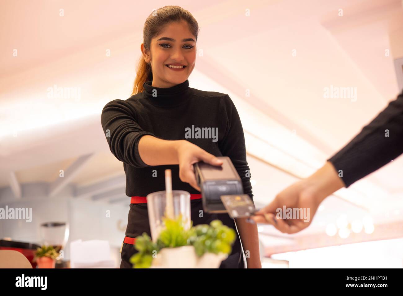 Waitress holding card reader while customer making payment through ...