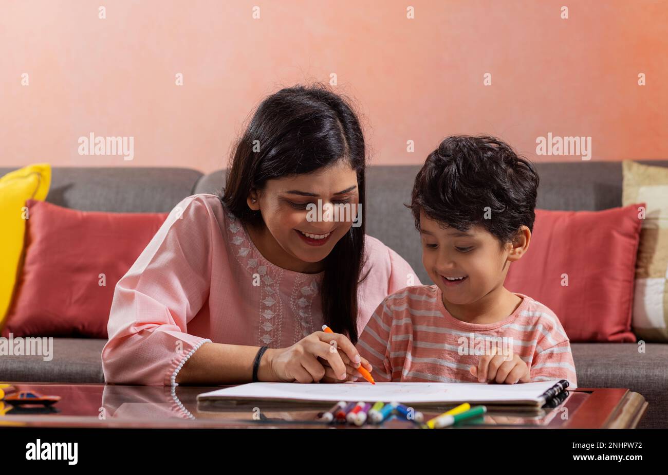 Mother helping her son with drawing Stock Photo - Alamy