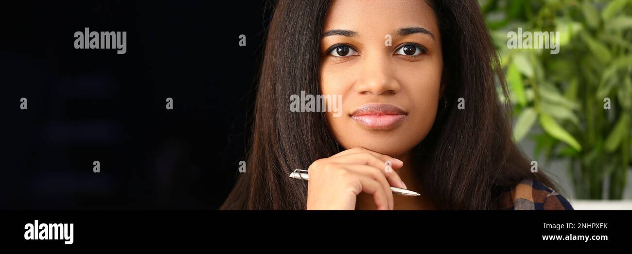 Thoughtful focused beautiful afro woman with pen Stock Photo - Alamy