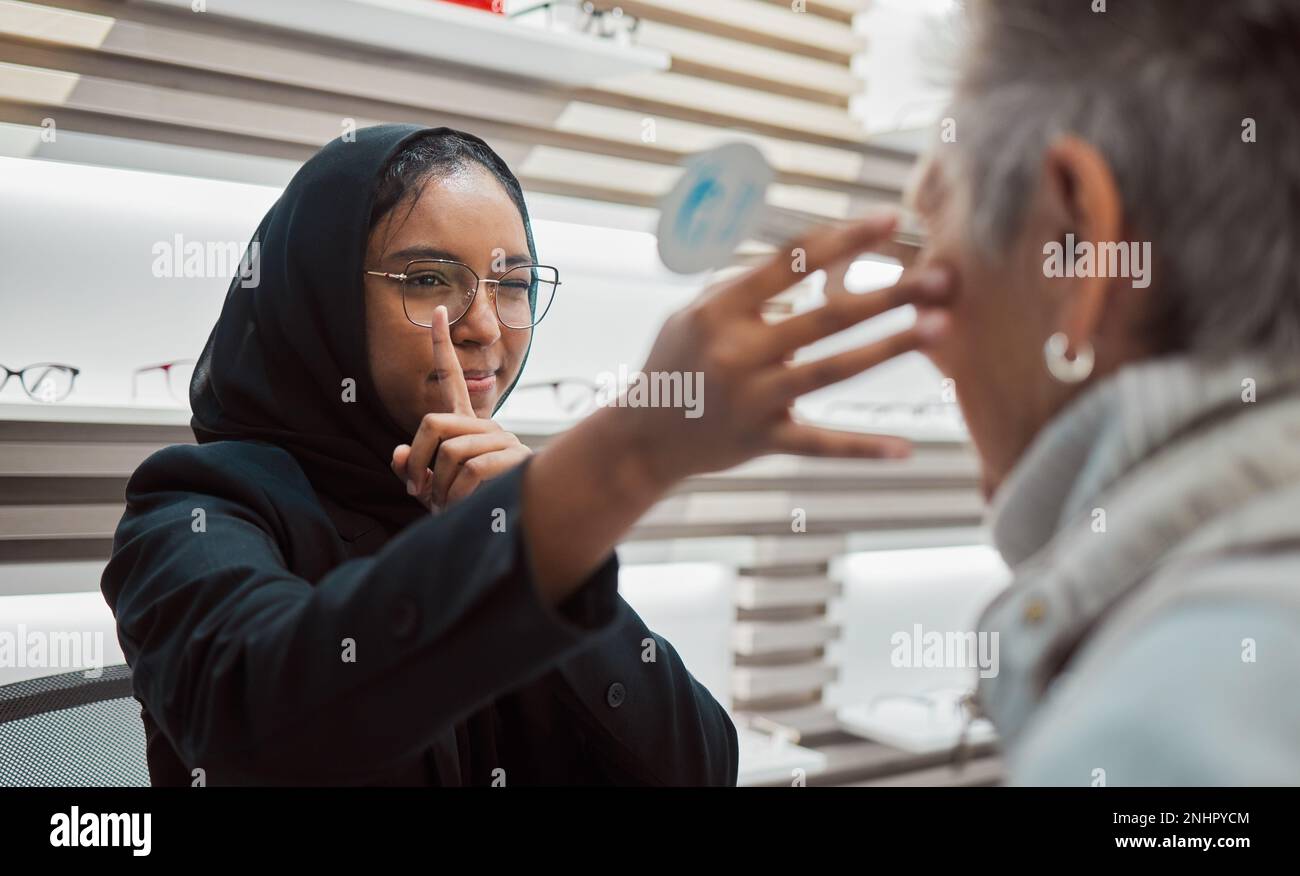Optometry, vision and eye test with an islamic woman optician working ...