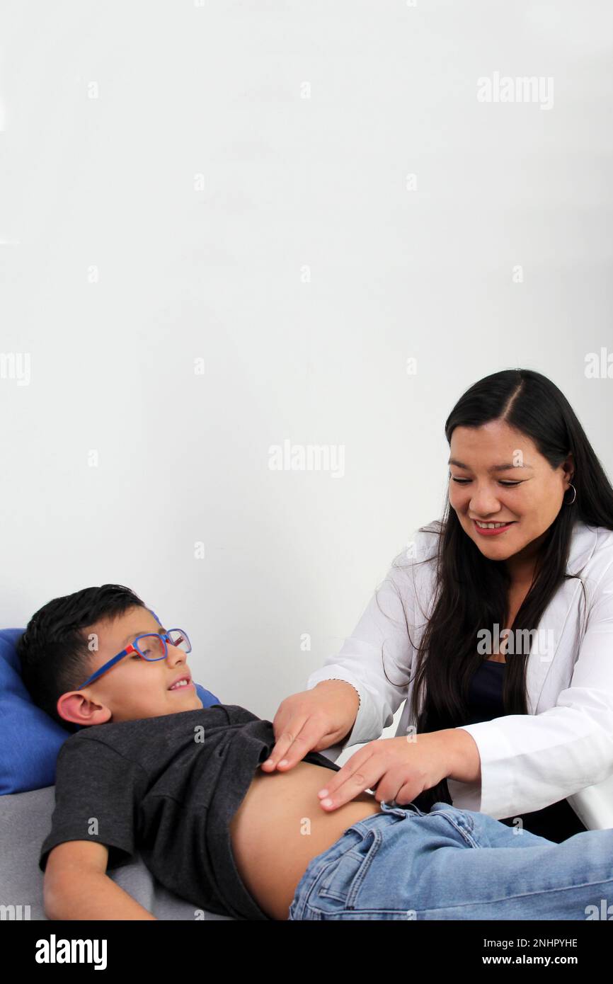 Latin woman doctor checks the belly of a child in her office to rule ...