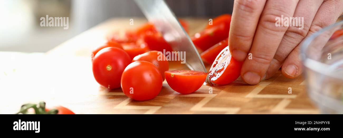 Closeup of man hand cutting tomato on cutting board at home Stock Photo ...