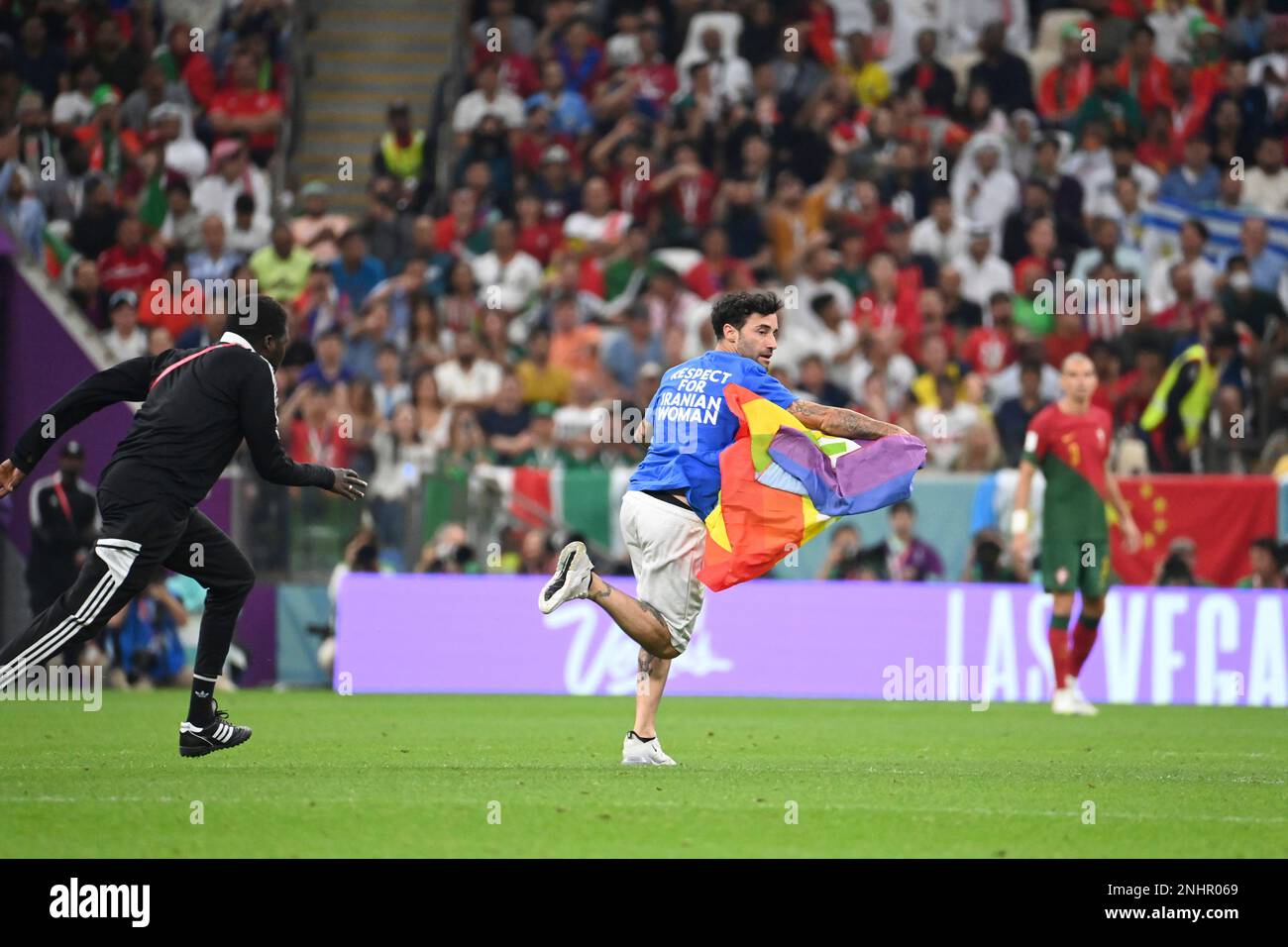 A pitch invader holding a rainbow flag runs onto the pitch during the ...