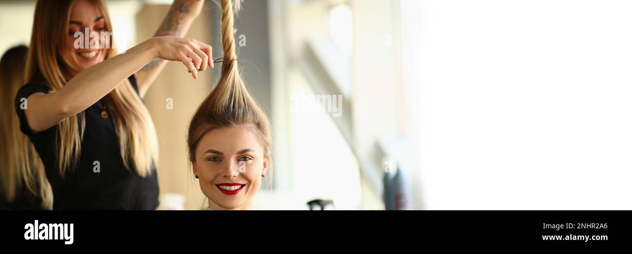 Professional female hairdresser stylist cuts hair of female client in ...