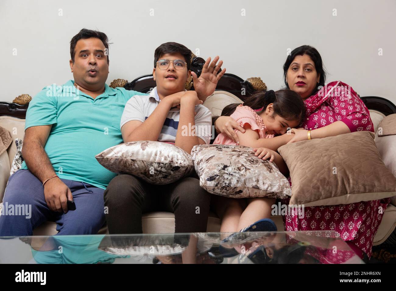 Family watching TV together while sitting on sofa in living room Stock ...