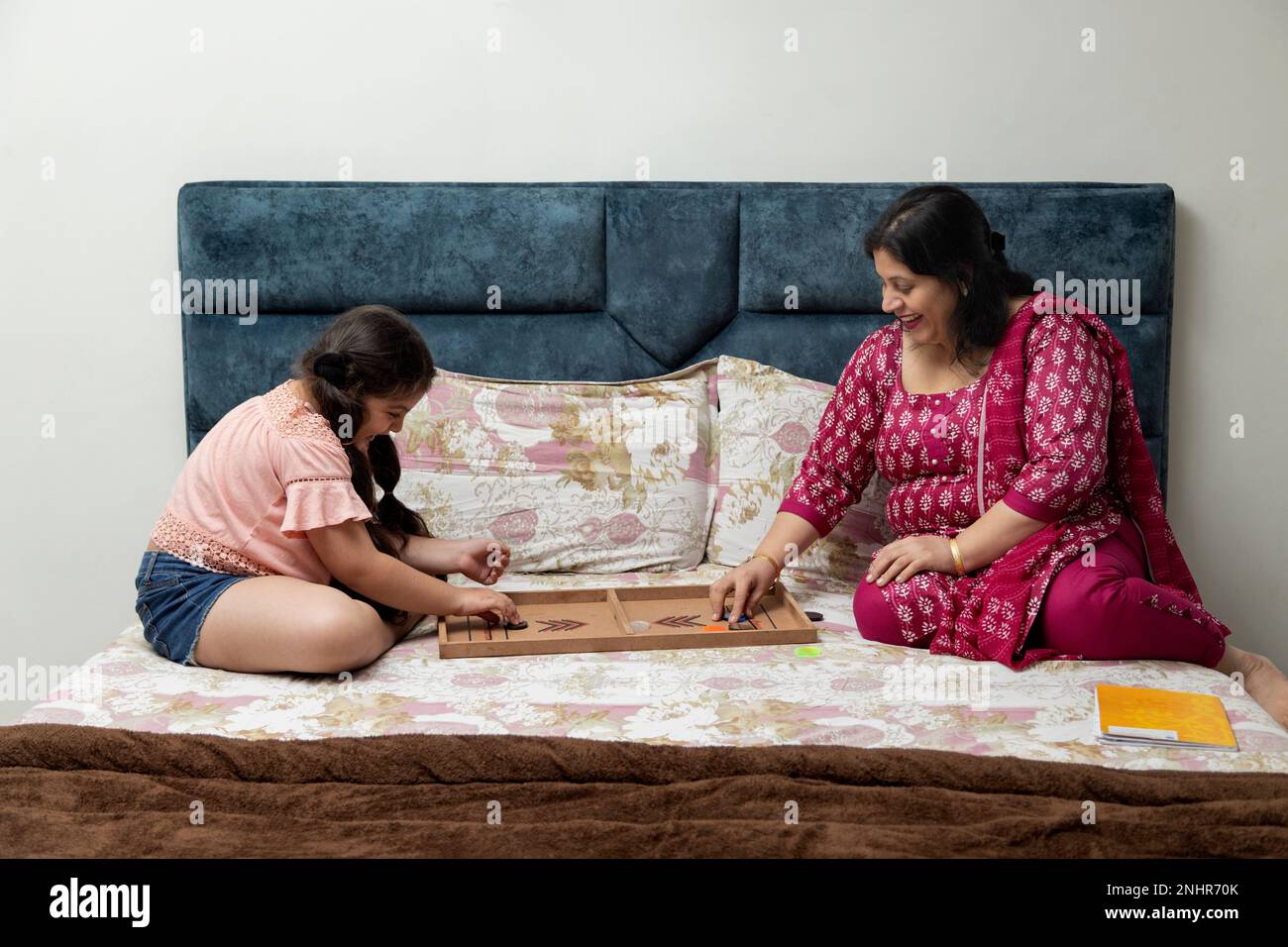 Mother and daughter playing fast sling puck on bed Stock Photo - Alamy