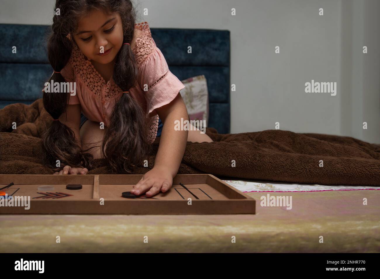 Little girl playing fast sling puck on bed Stock Photo - Alamy