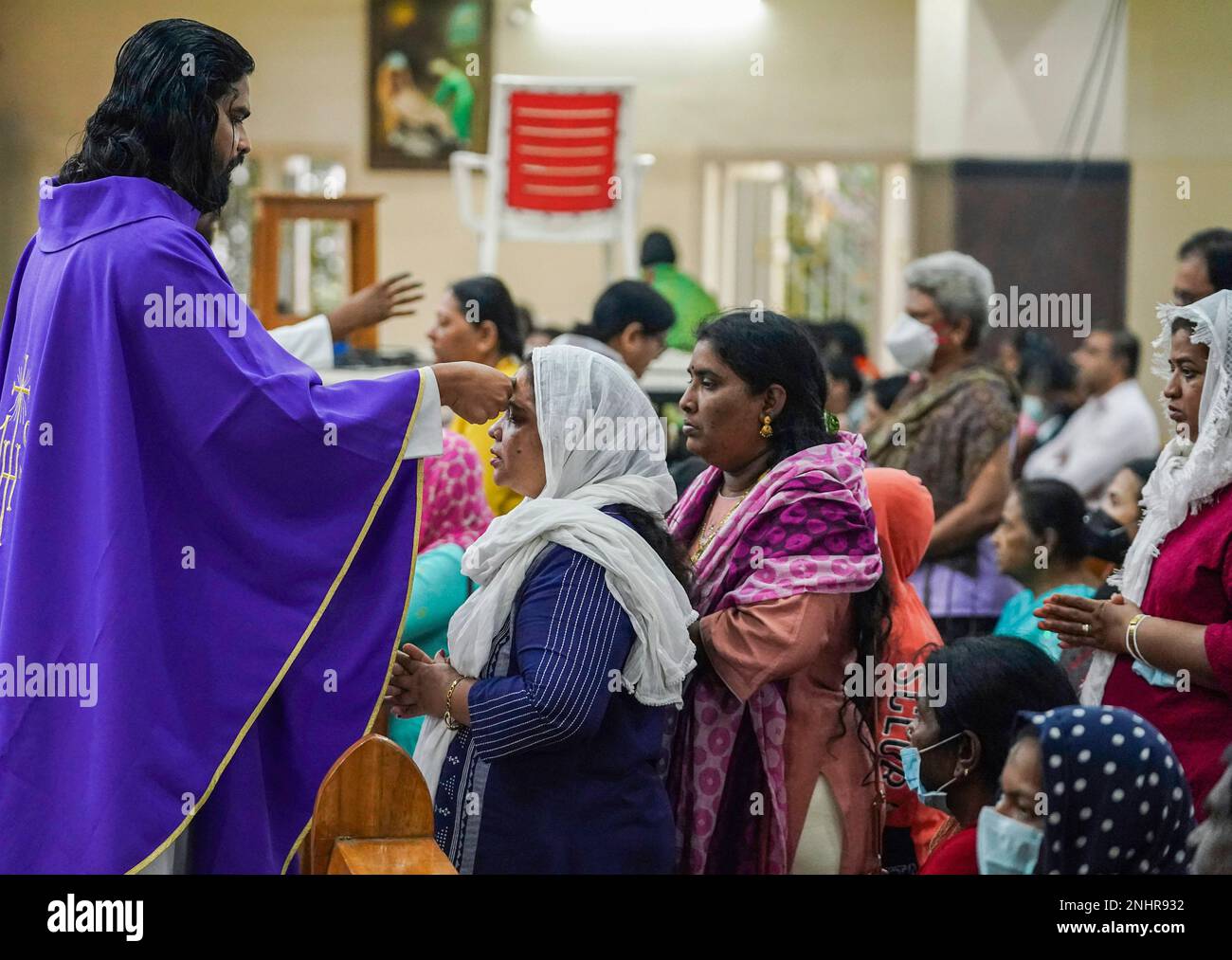 A Catholic priest marks the forehead of a devotee with the symbol of a ...